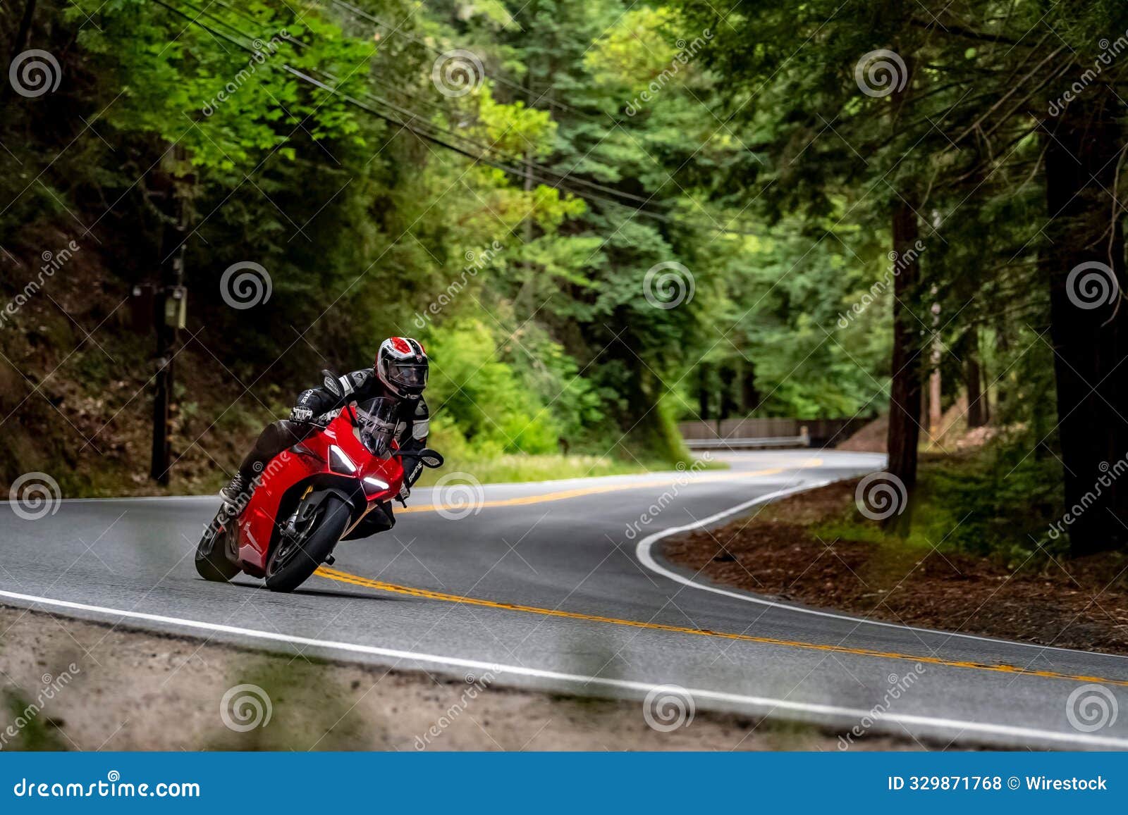 Man Riding a Ducati Motorcycle through the Woods on a Winding Road ...