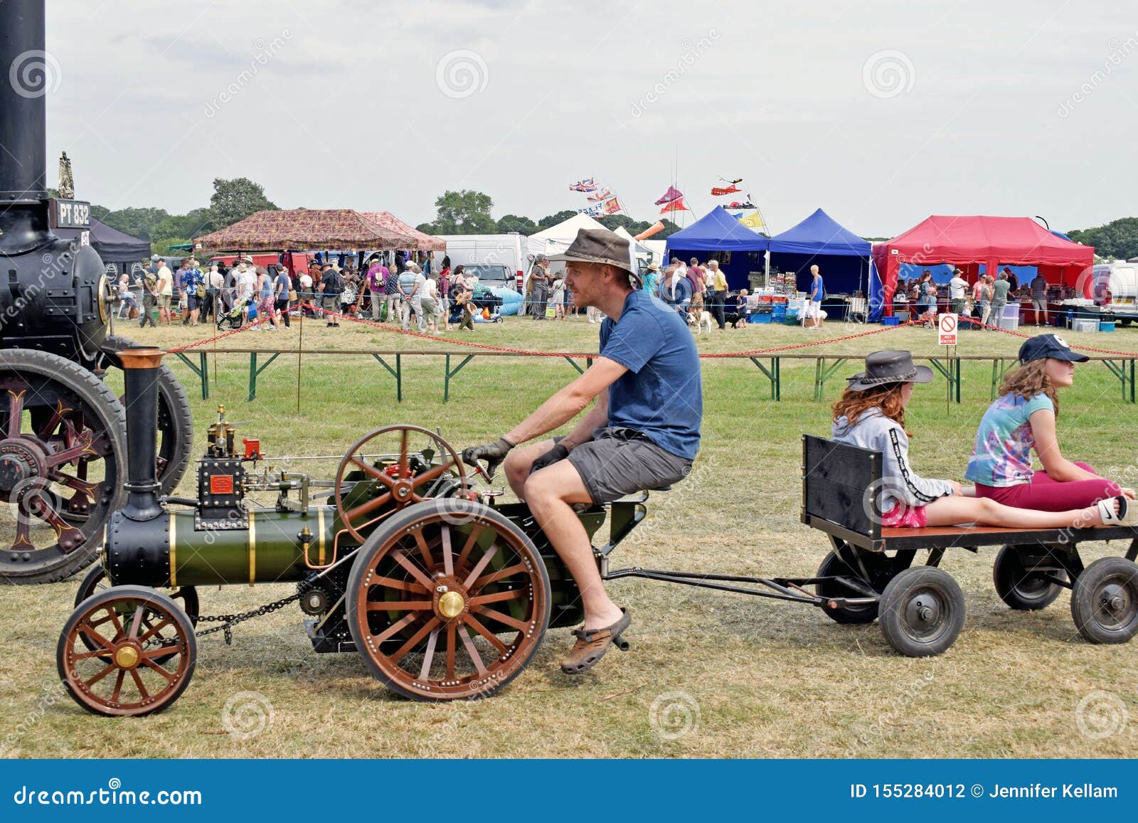 A Man Riding a Mini Steam Engine with a Trailer on the Back Pulling Two ...