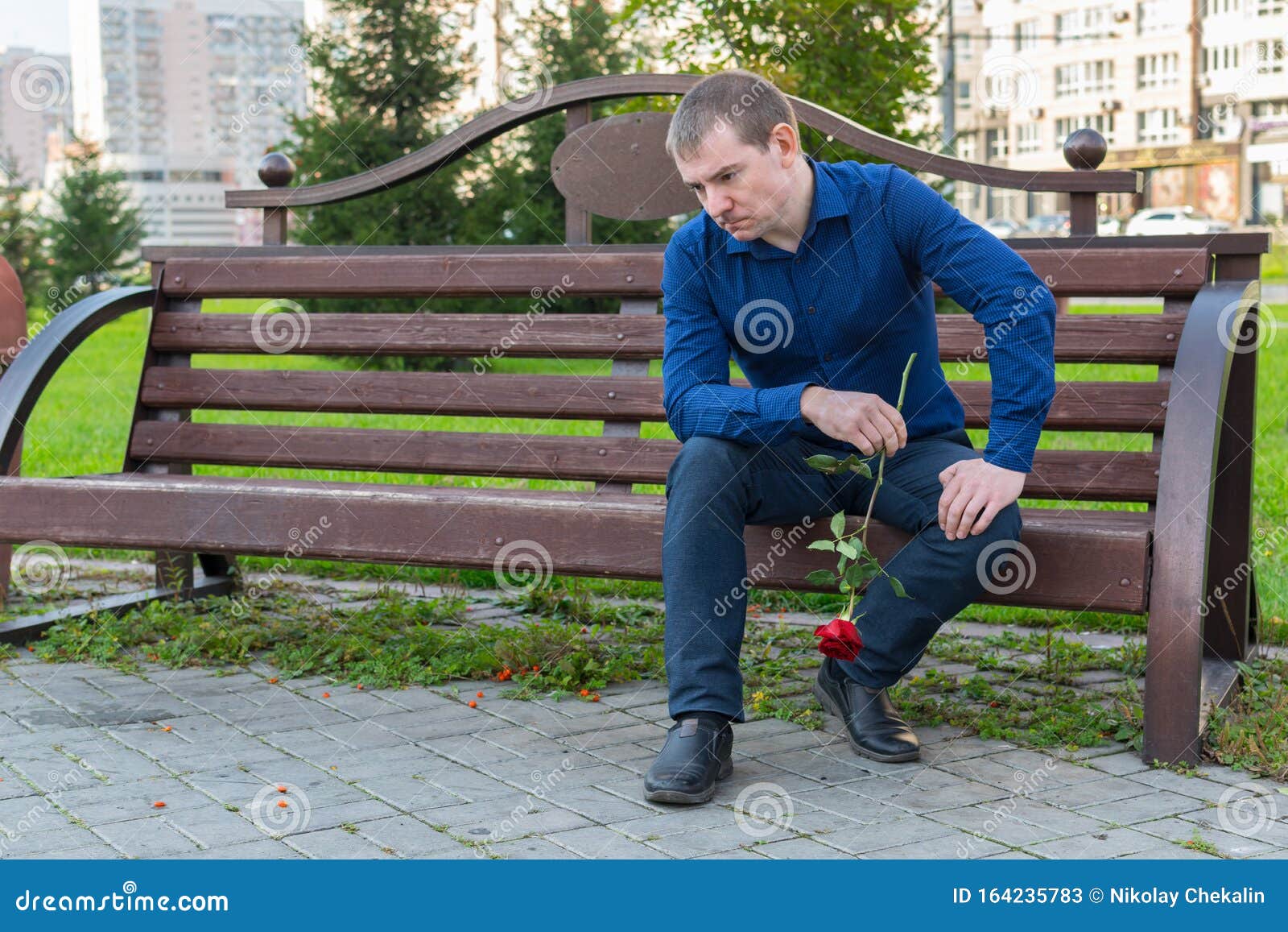 A Sad Man with a Rose in His Hands Sits on a Bench after Parting with ...
