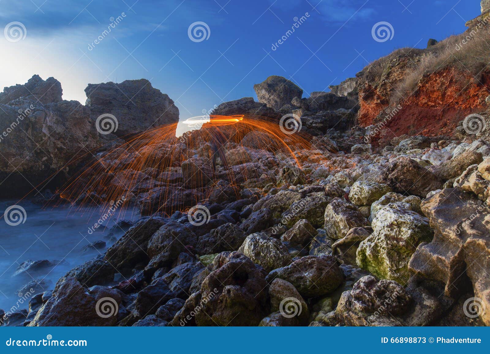 Man Rotating Fire on Rocky Shore Stock Image - Image of dark, evening ...