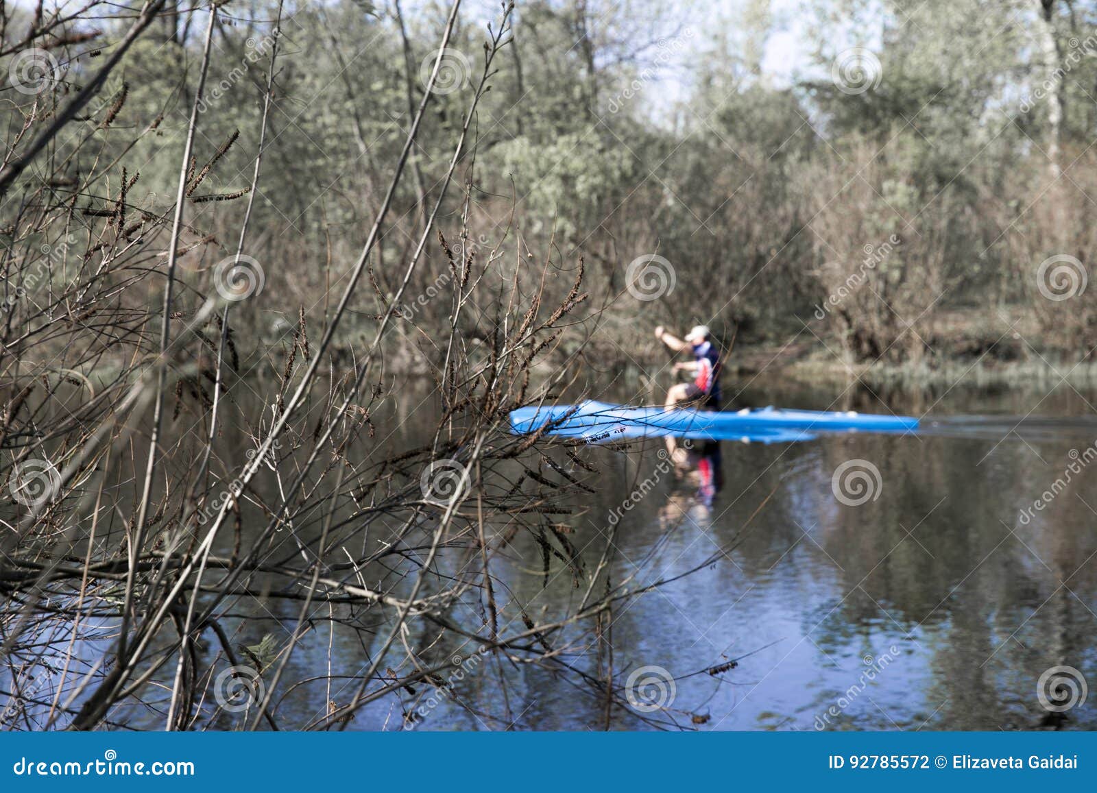 A Man Rowing in Canoe on a Calm River Whose Banks are Covered W Stock ...