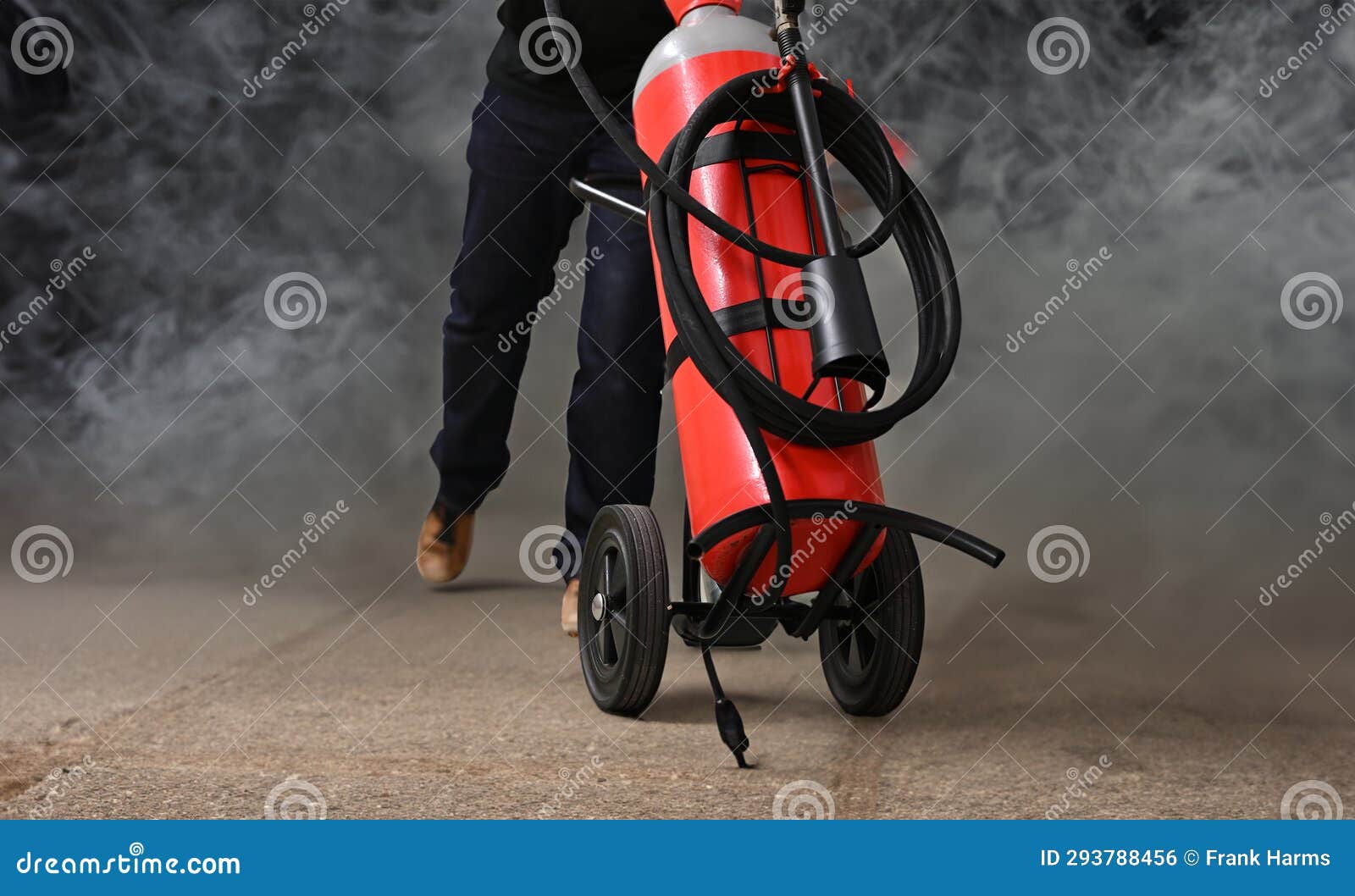 Man Runs with a Movable Fire Extinguisher through Smoke during a ...