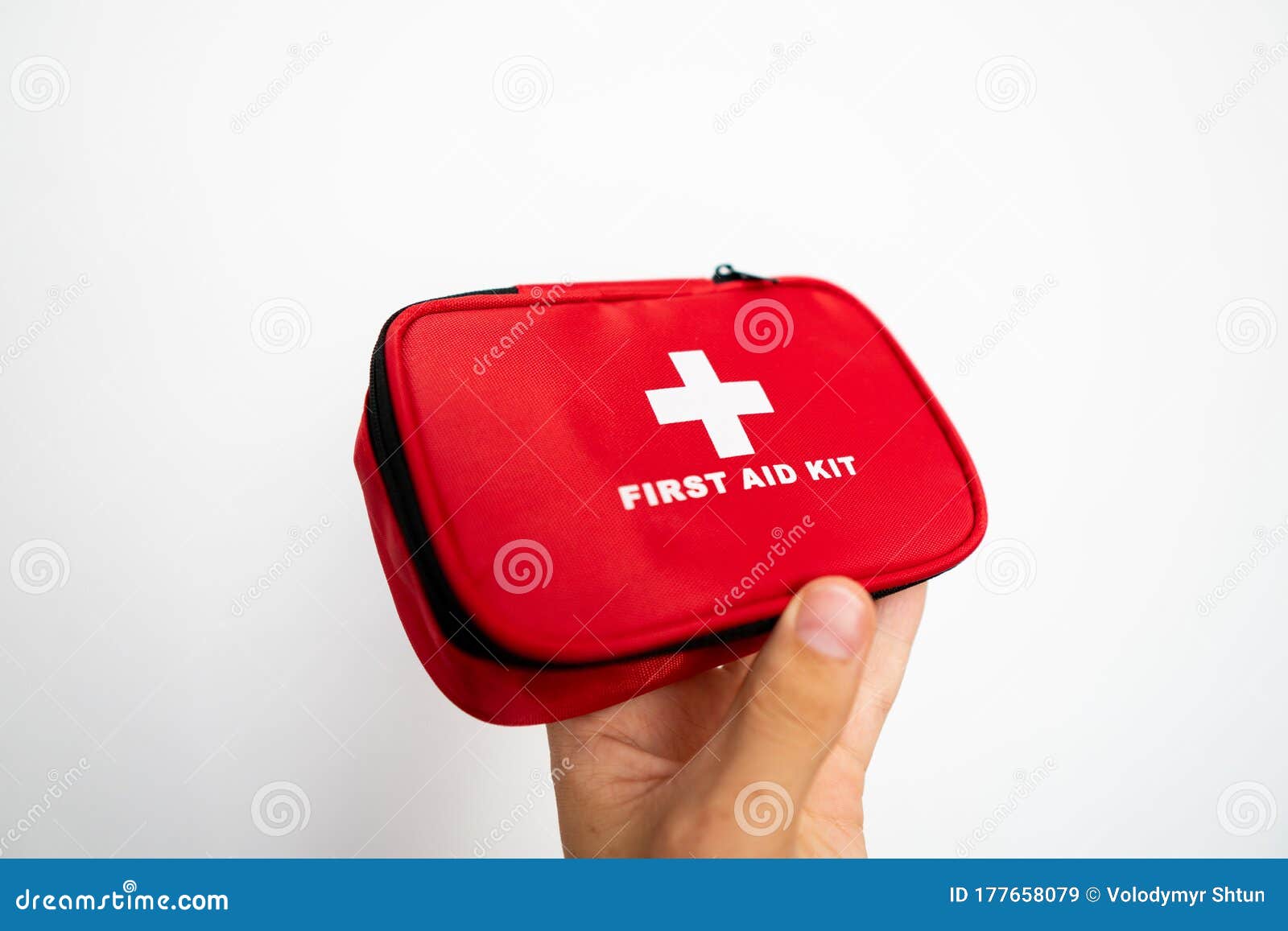 Man`s Hand Holding a Red First-aid Kit with a White Wall on Background ...