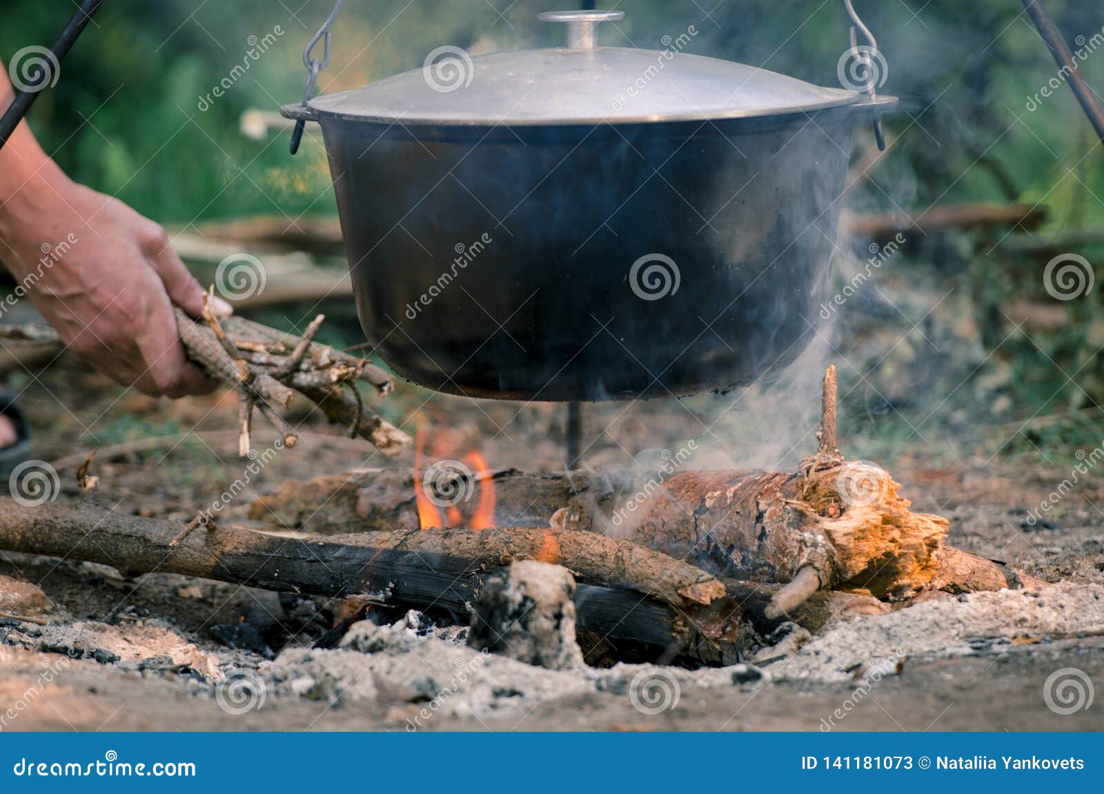 A Man S Hand Kindles a Fire Under a Pan, Which Stands on a Fire Stock ...