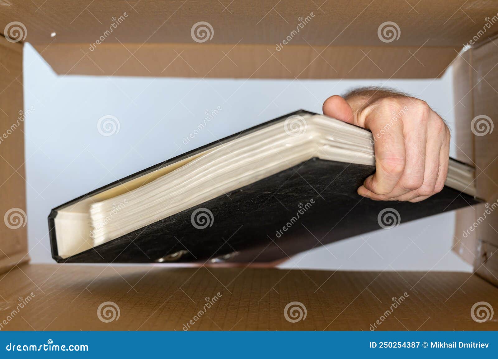 A Man`s Hand Pulls a Ring Binder Folder Out of a Cardboard Moving Box ...