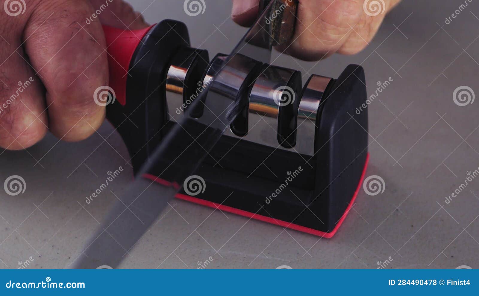 A Man S Hand Sharpens a Kitchen Knife in a Special Sharpener on the ...