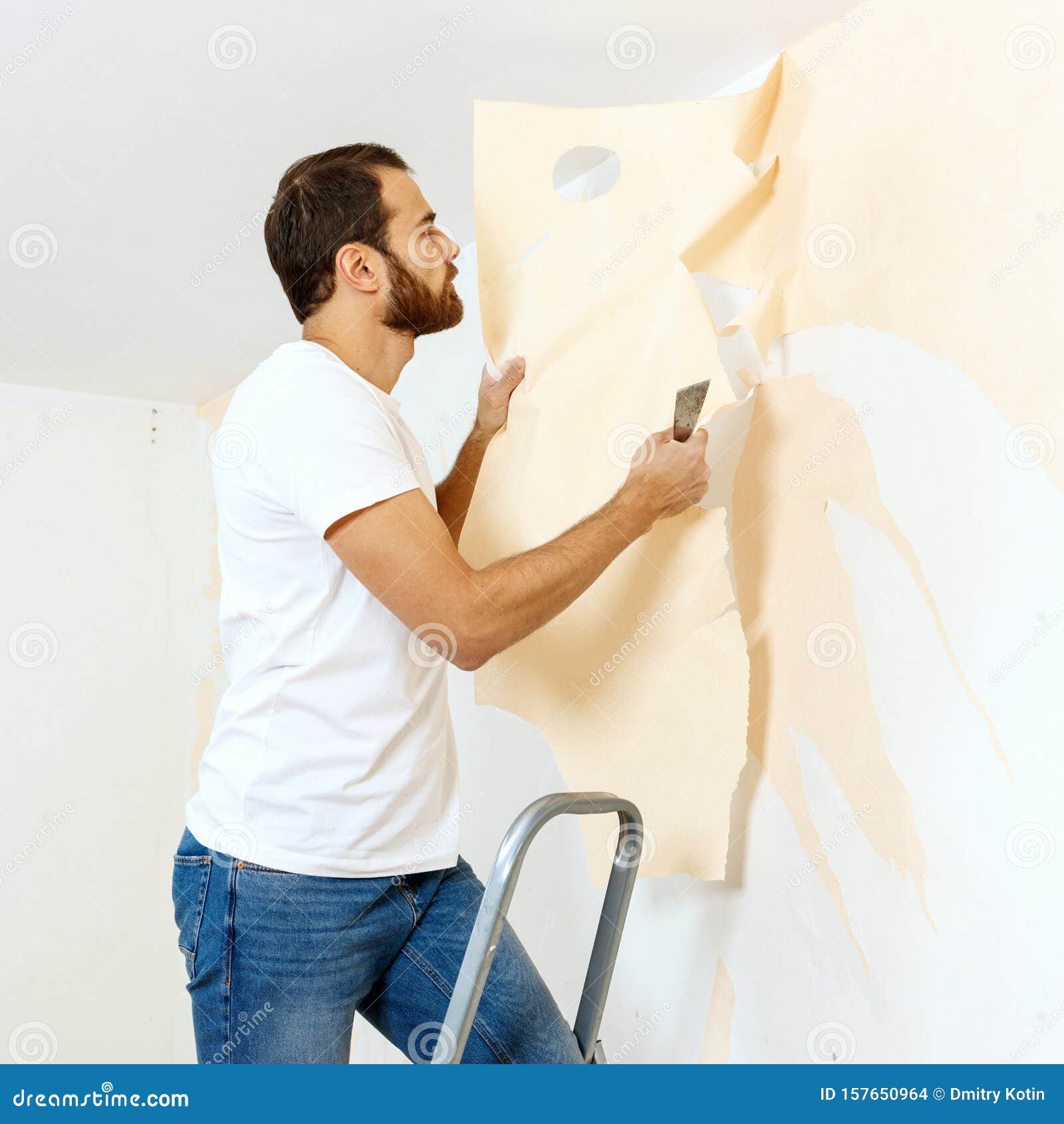 Man in with a Scraper in the Process of Removing Old Wallpaper. Stock ...