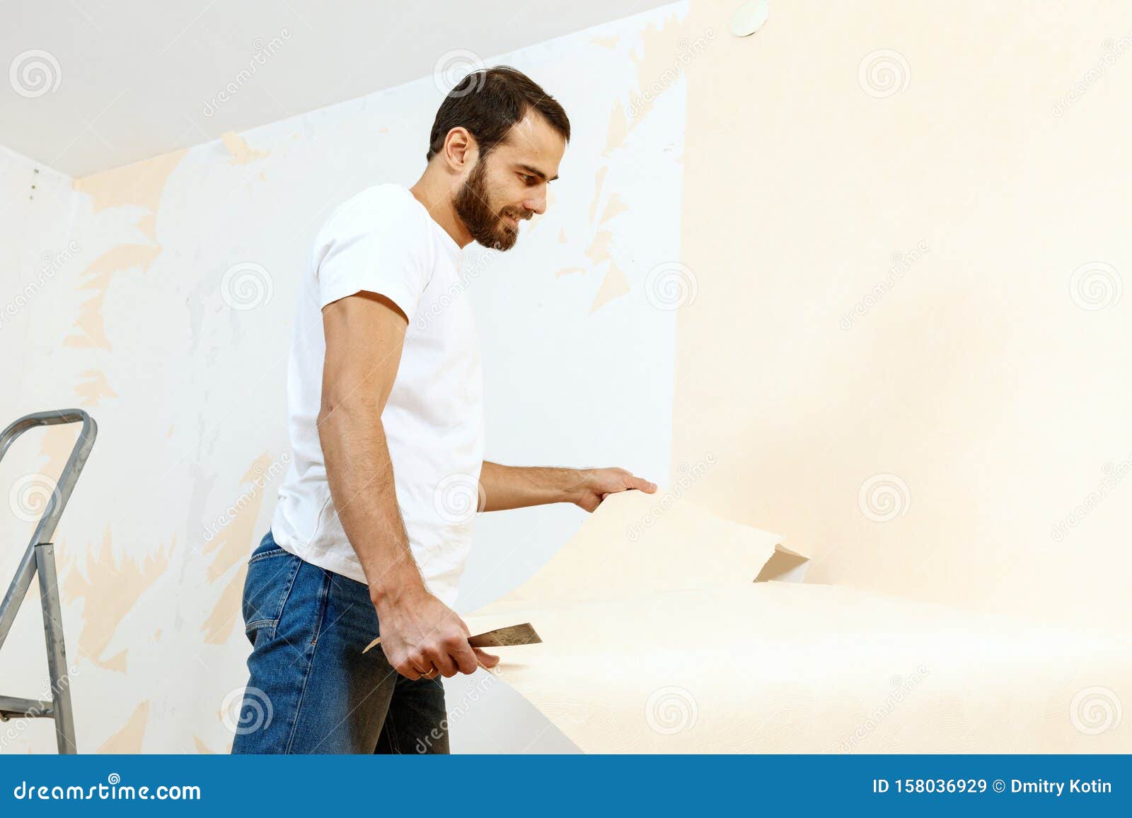 Man in with a Scraper in the Process of Removing Old Wallpaper. Stock ...