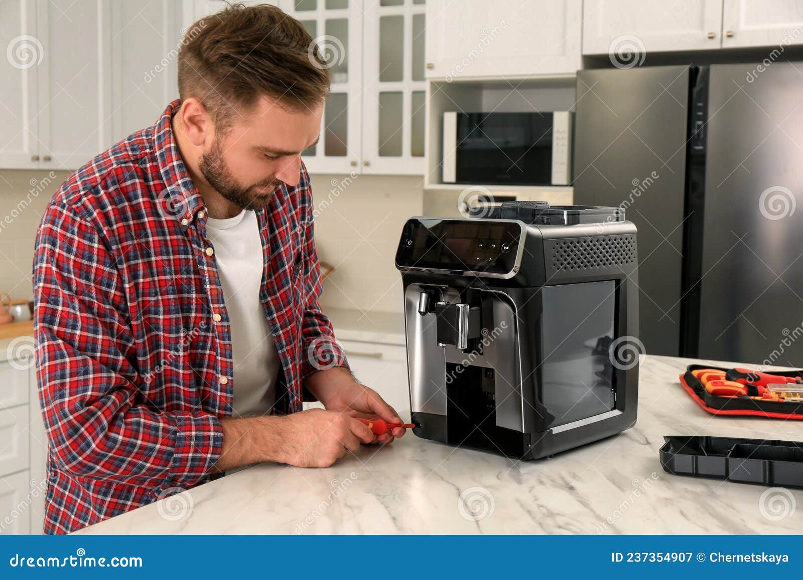 Man with Screwdriver Fixing Coffee Machine at Table in Kitchen Stock ...