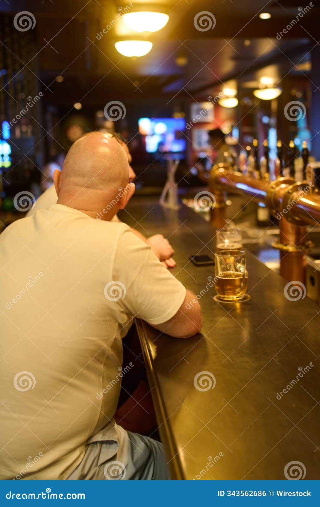 A Man Sitting at a Bar with a Tall Glass on the Bar Stock Photo - Image ...