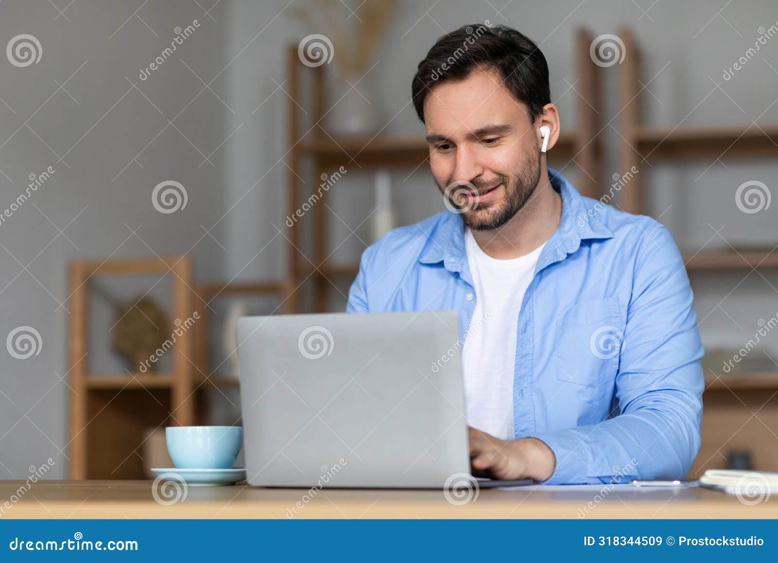 Man Sitting at Table Using Laptop and Earbuds Stock Image - Image of ...