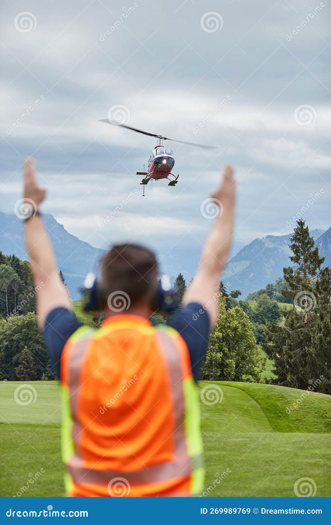 Man Seen from Behind Instructing Landing Helicopter in the Alps ... Man Seen from Behind Instructing Landing Helicopter in the Alps ...