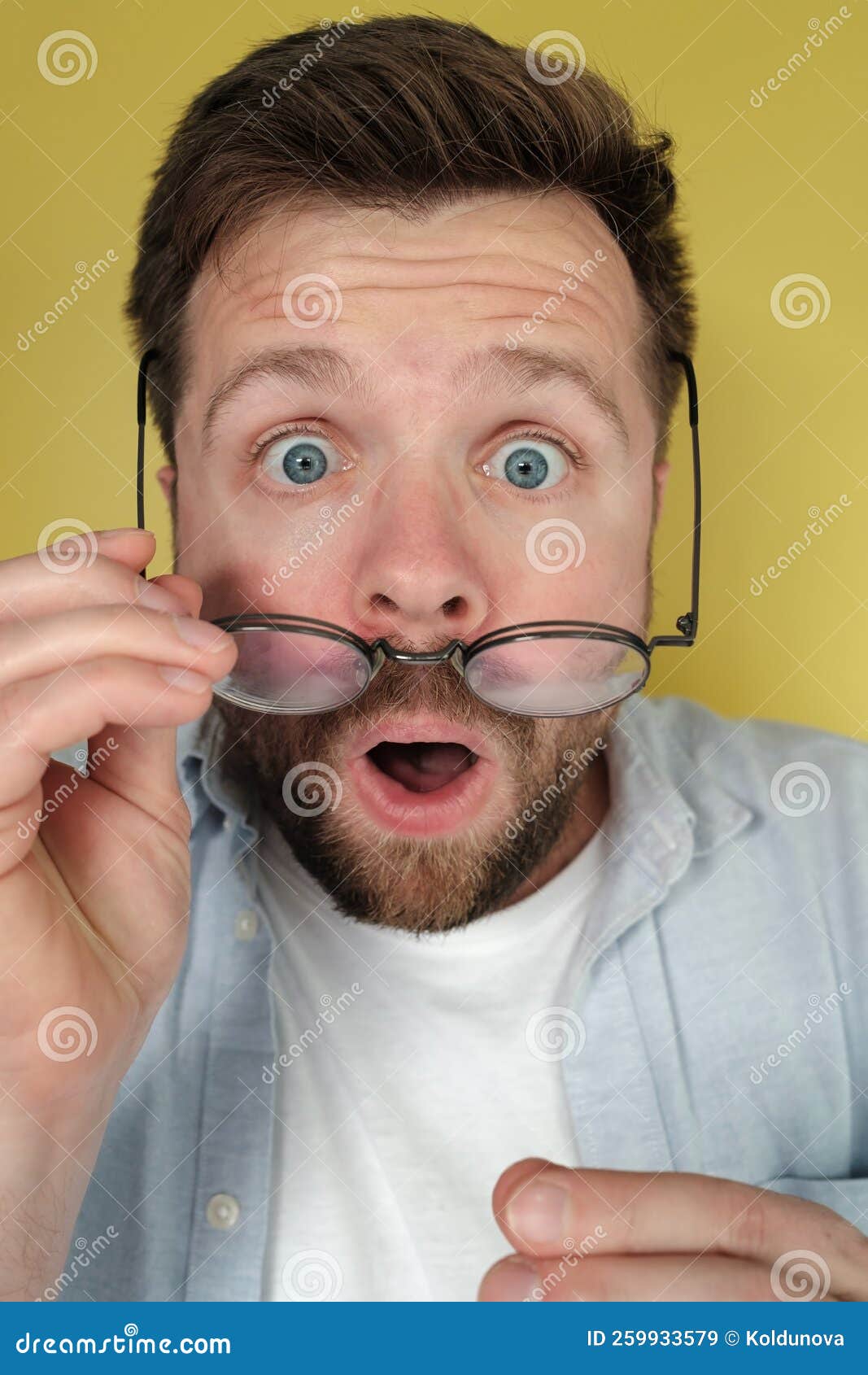 Man With A Shocked Expression Holds His Glasses Which He Took Off In