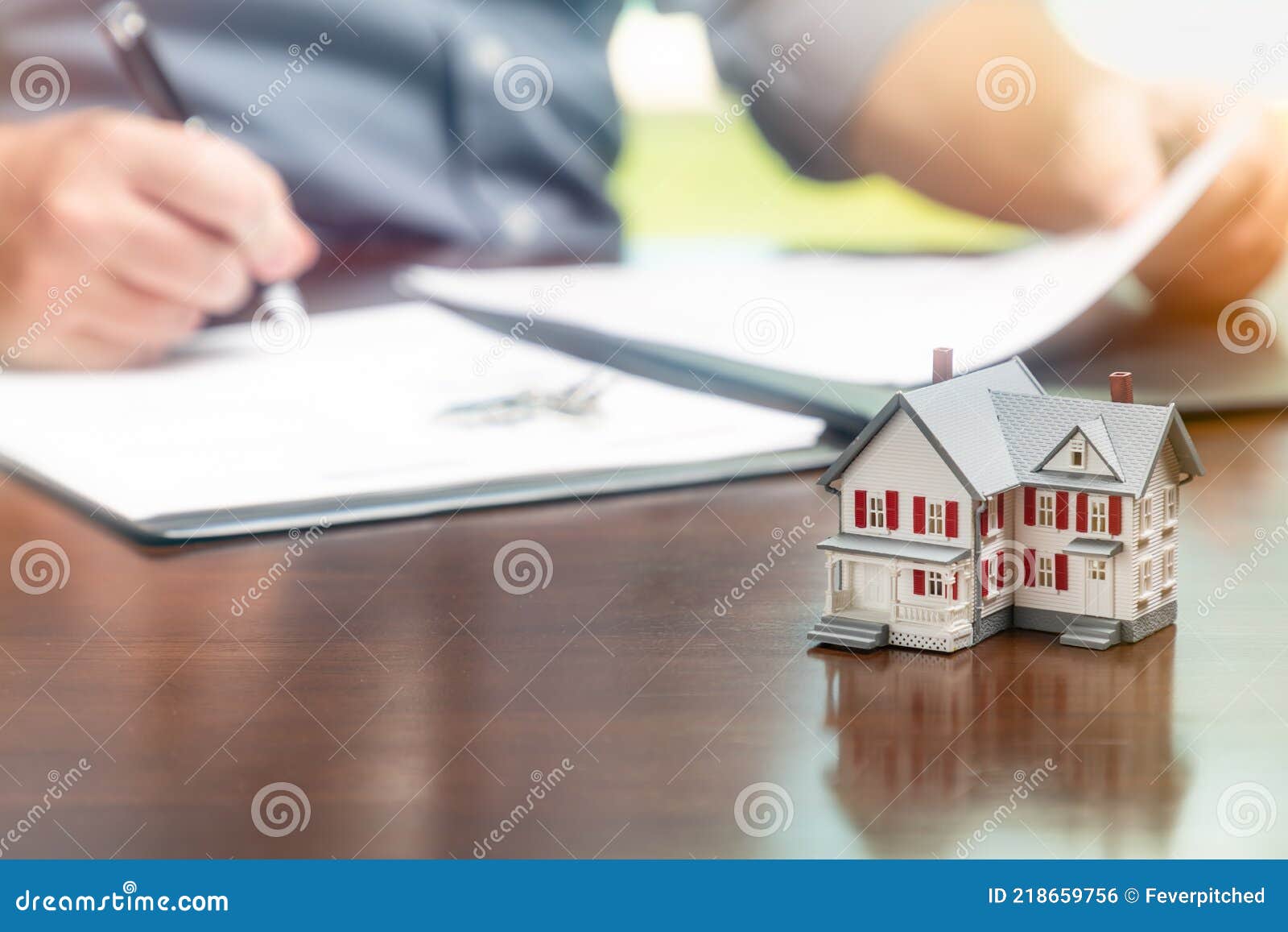 Man Signing Real Estate Contract Papers with Small Model Home in Front ...