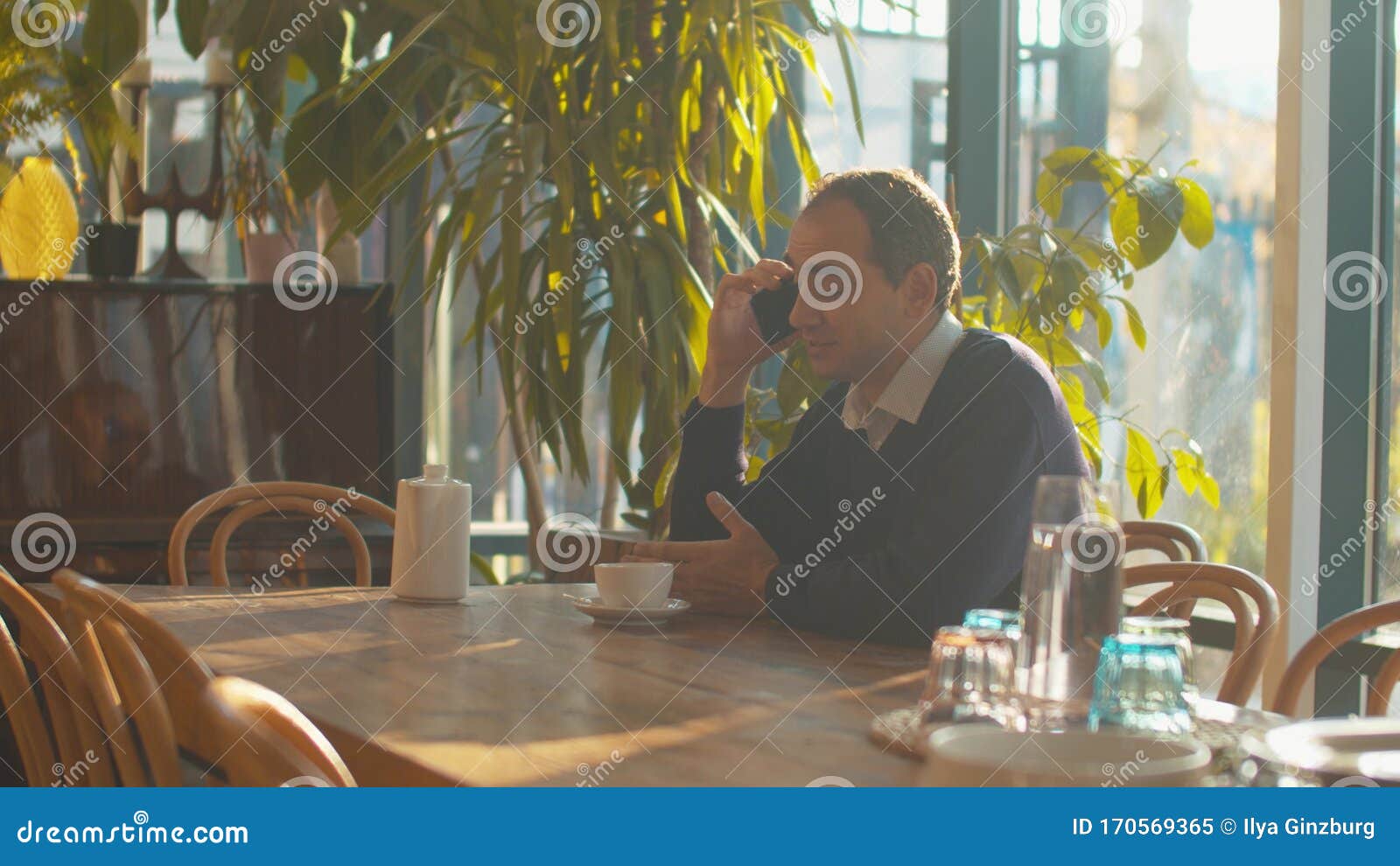 Man Sit at a Table in Cafe and Talk on Phone Stock Image - Image of ...