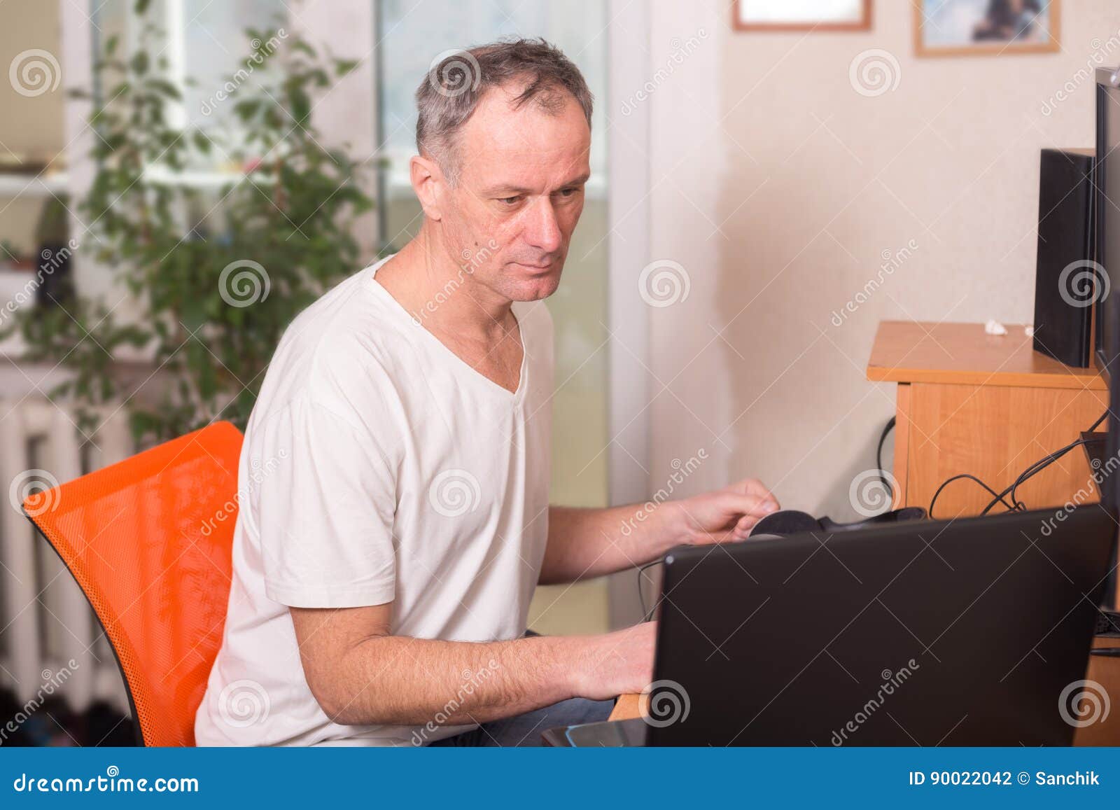Man Sits between a Laptop and a Computer, Looking at the Screen Stock ...