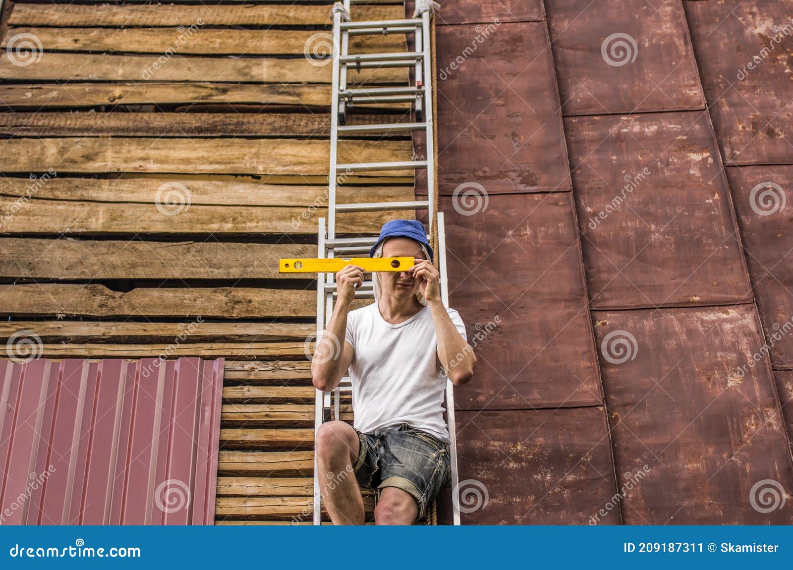A Man Sits on the Roof on a Ladder with a Building Level Stock Image ...