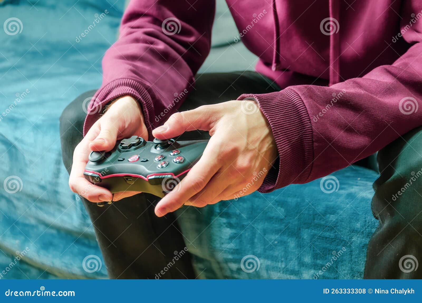 Man Sits on Sofa Holding Game Controller, Playing Remote Controlled ...