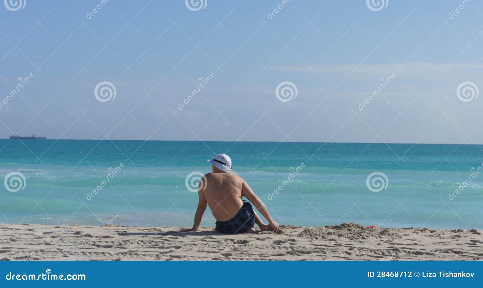 Man sitting on the beach stock photo. Image of landmark - 28468712