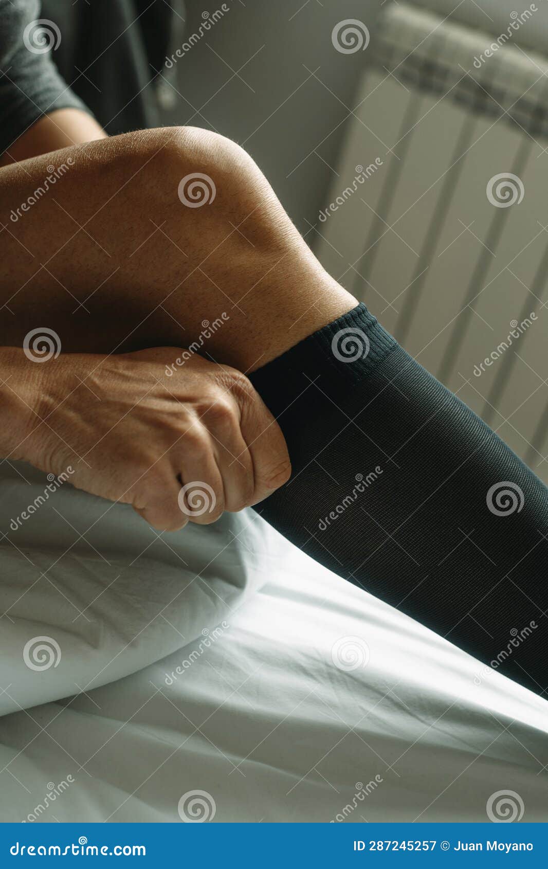 Man Sitting on the Bed Puts on a Compression Sock Stock Image - Image ...