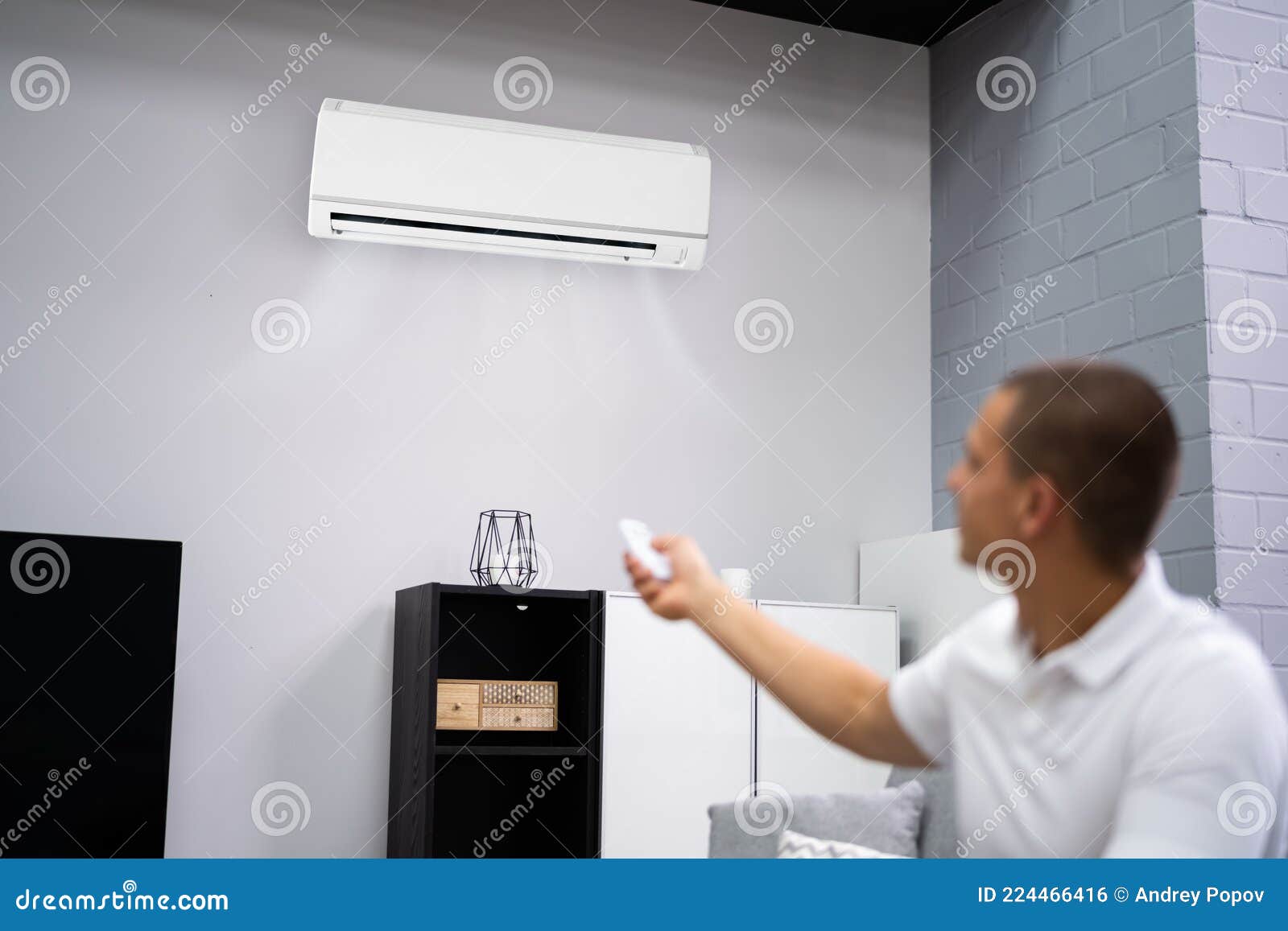 Man Sitting on Couch Operating Air Conditioner Stock Photo - Image of ...