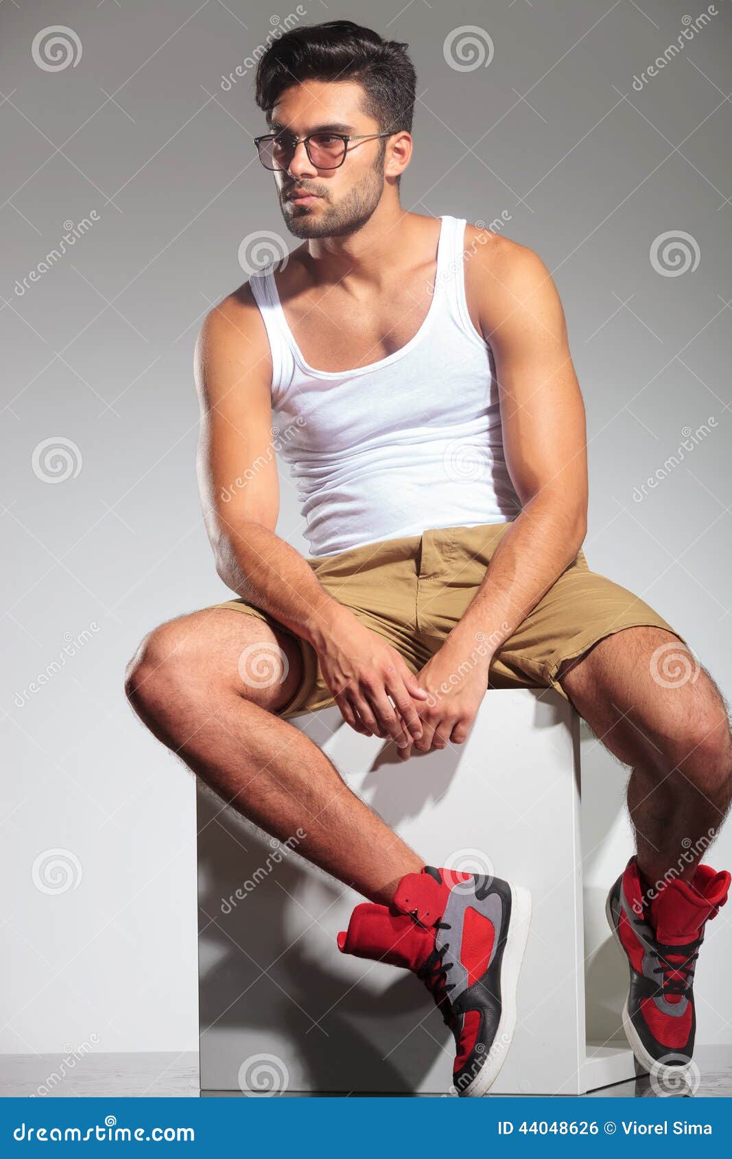 Man Sitting on a Cube and Looking To Side Stock Photo - Image of shorts ...