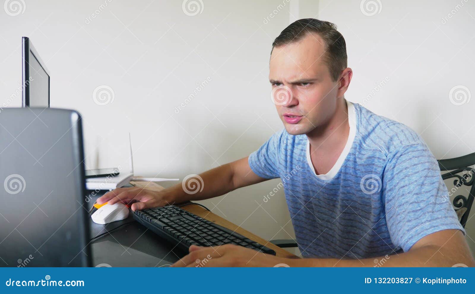 A Man Sitting at a Desk at Home, Working at Home Computer and Laptop ...