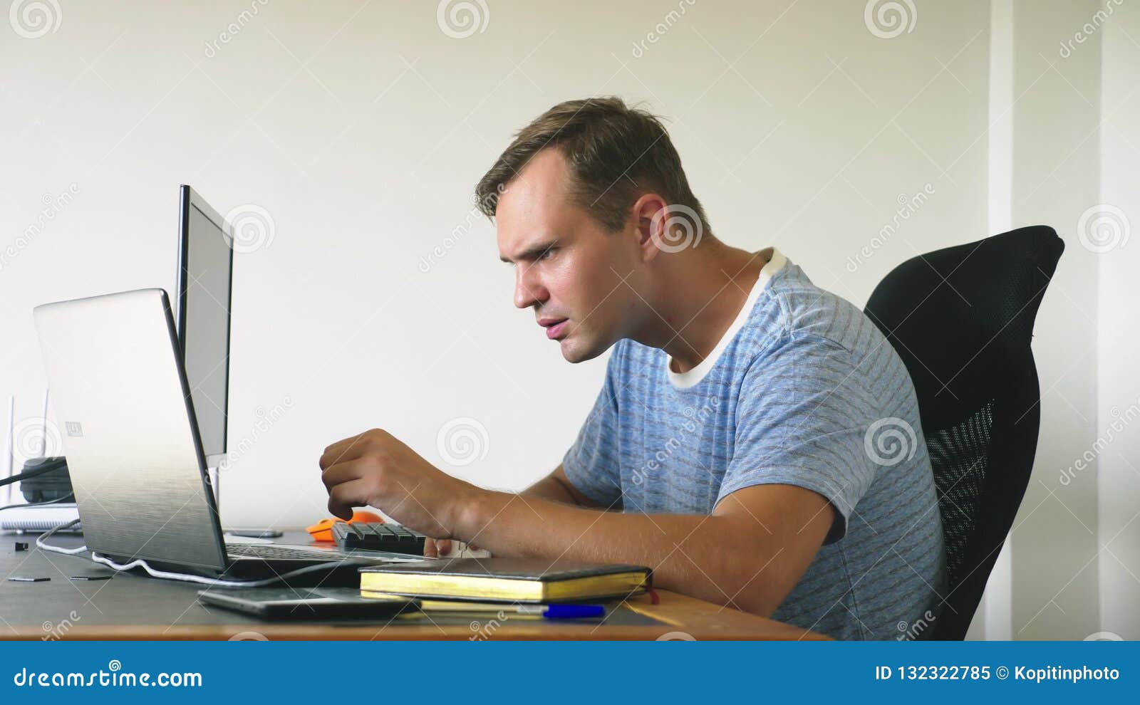 A Man Sitting at a Desk at Home, Working at Home Computer and Laptop ...