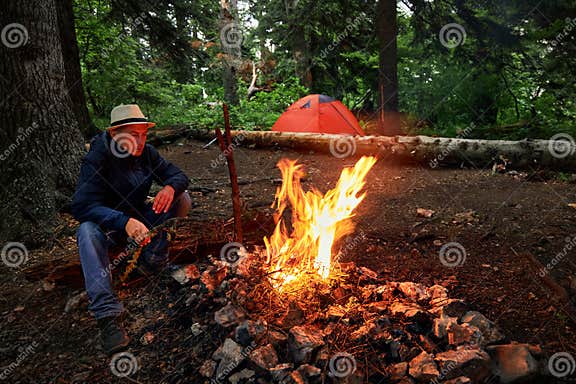 Man Sitting by a Fire while Camping in the Woods Stock Image - Image of ...