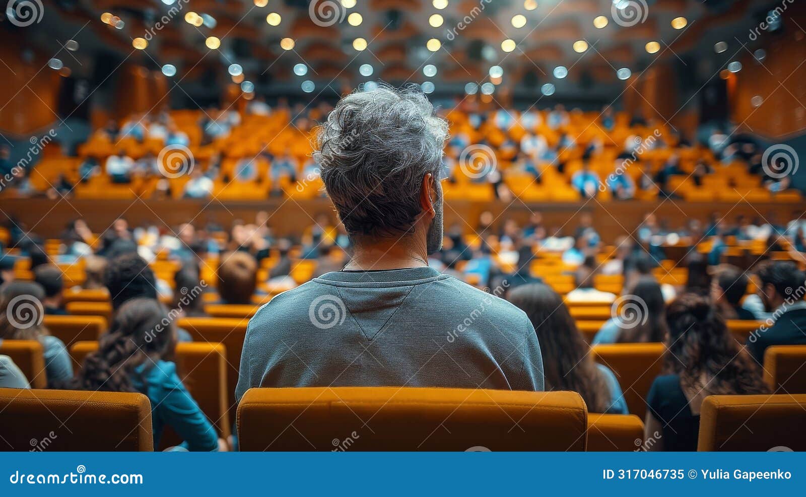 Man Sitting in Front of Packed Auditorium Stock Image - Image of ...