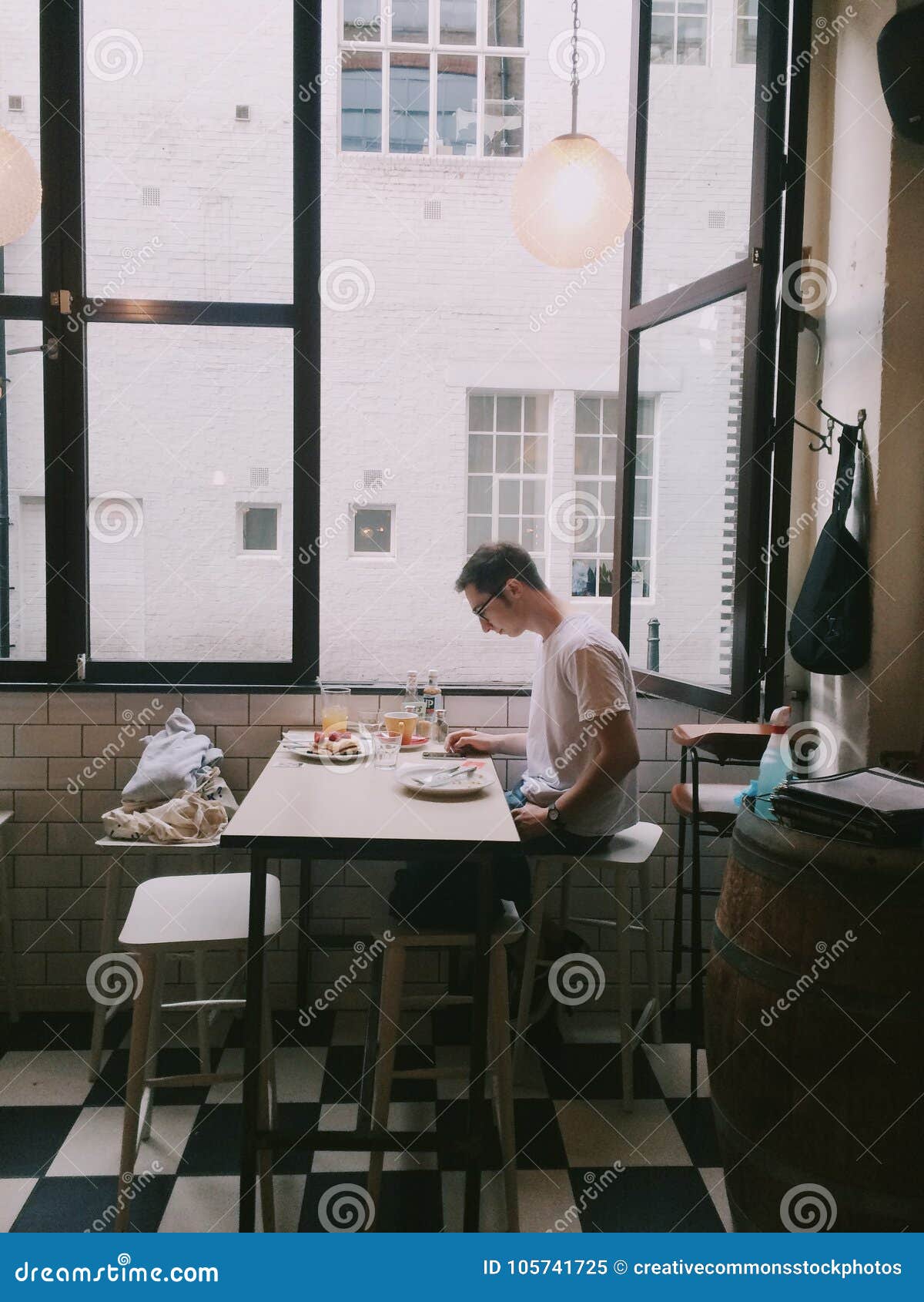 Man Sitting In Front Of Table Holding Smartphone Beside Window Picture ...