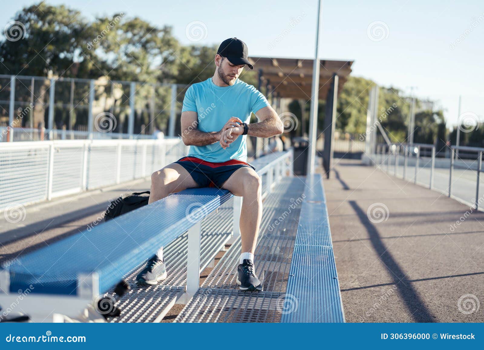 Man Sitting on a Park Bench Using a Smartwatch Stock Photo - Image of ...