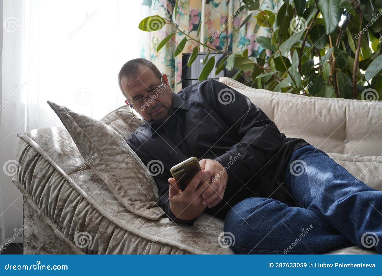 Man Sitting on Sofa and Looking at Smartphone Stock Image - Image of ...