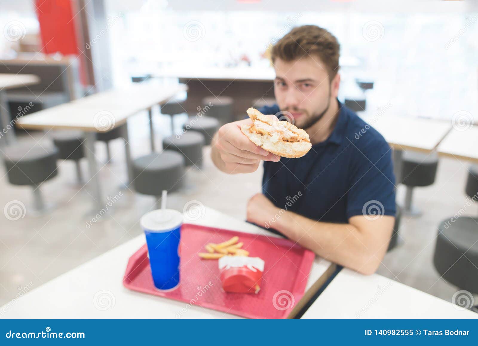 Man is Sitting at a Table in a Restaurant with a Tray of Food and ...