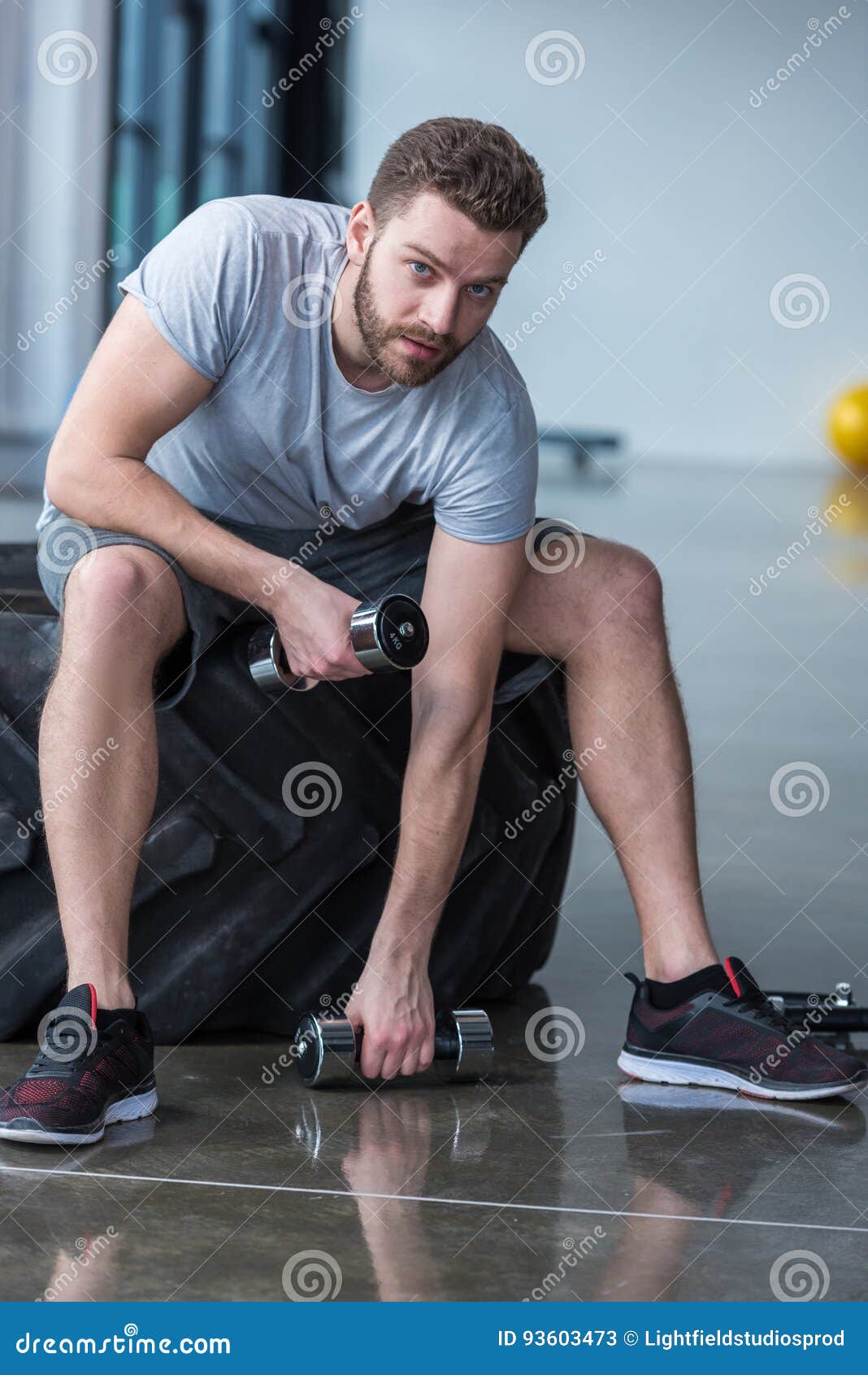 Man Sitting on Tyre and Exercising with Small Dumbbells Stock Image ...