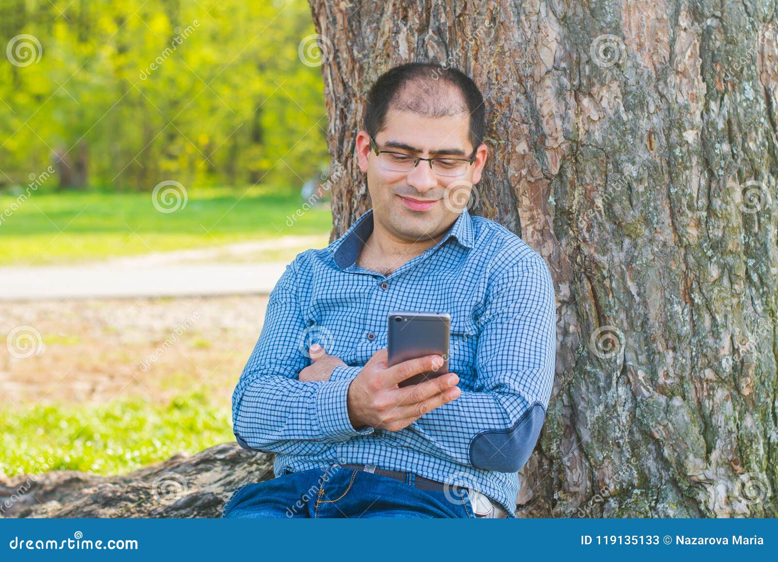 Young Man Sitting Under a Tree Stock Image - Image of male, happy ...
