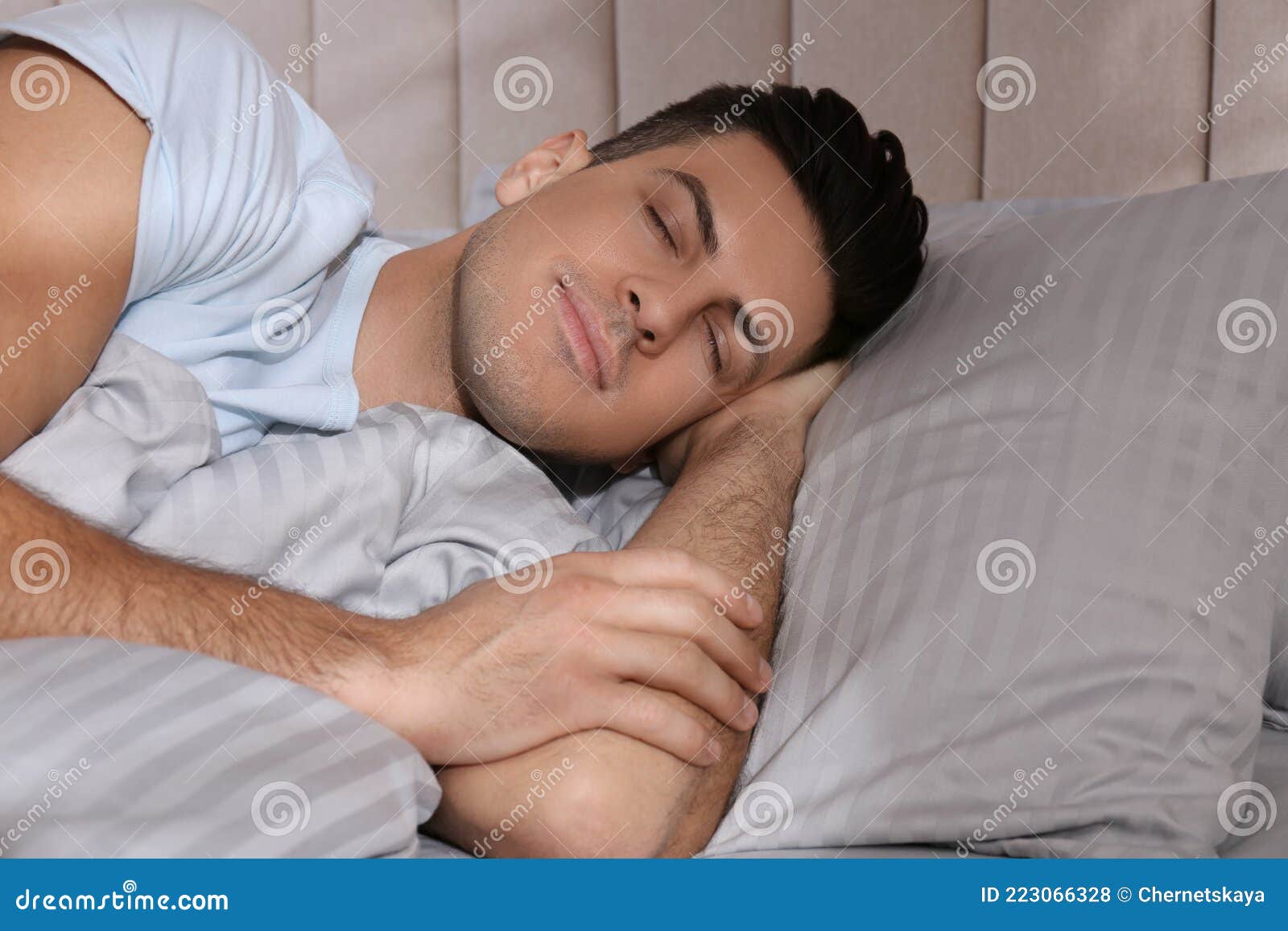 Man Sleeping in Comfortable Bed with Grey Striped Linens Stock Photo ...