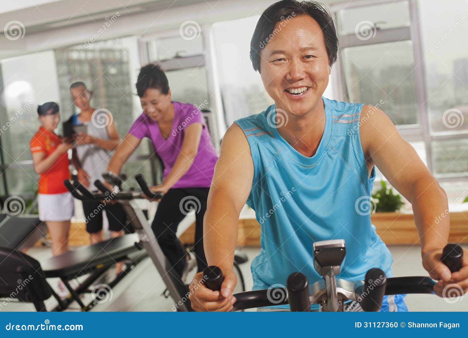 Man Smiling and Exercising on the Exercise Bike at the Gym, Looking at ...