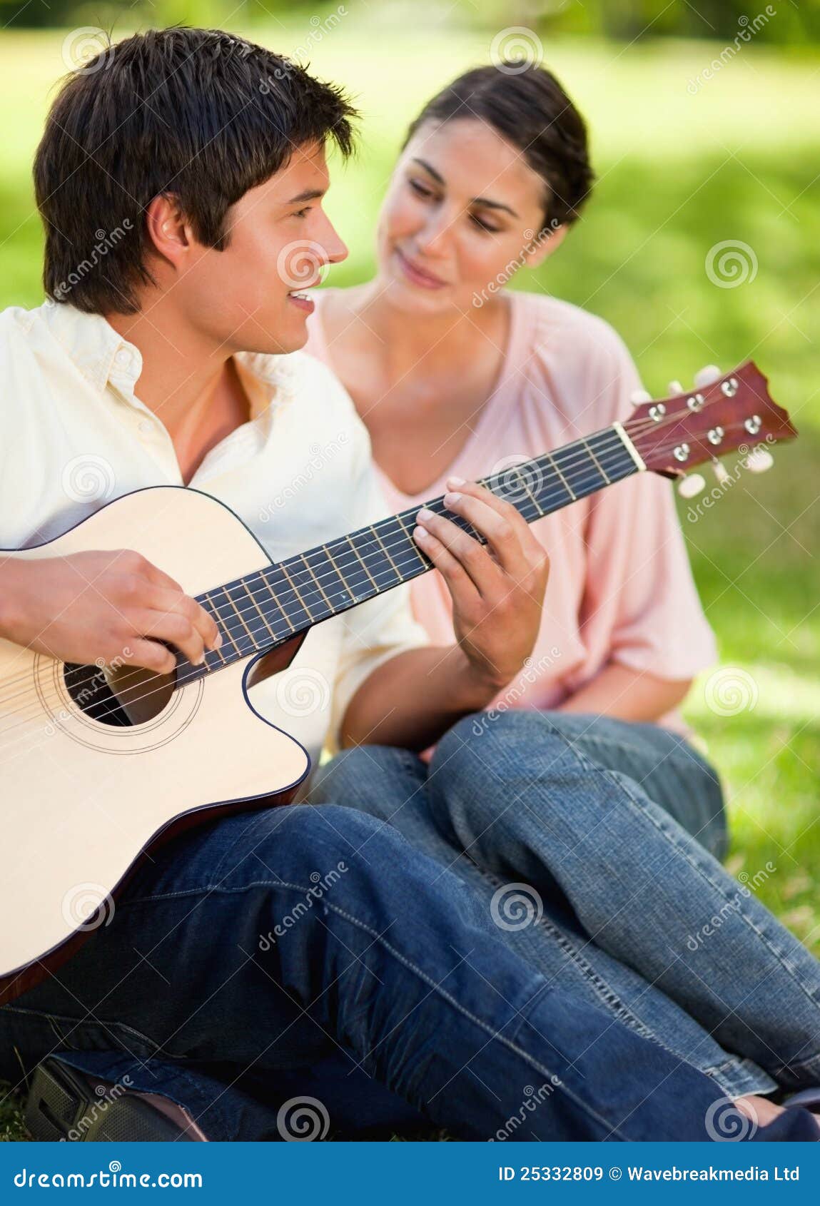 Man Smiling while Playing the Guitar while he is Being Watched B Stock ...