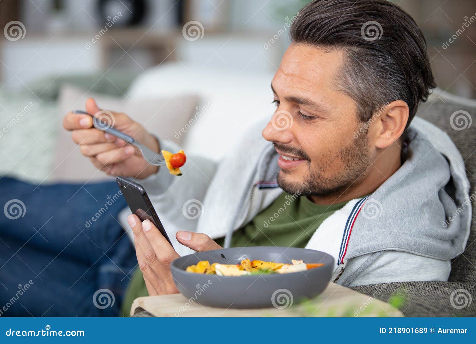 Man on Sofa Using Smartphone while Eating Stock Image - Image of ...