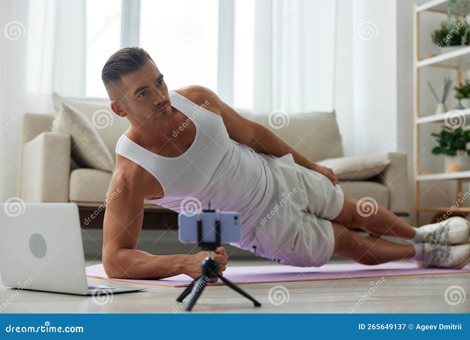 Man Sports Watching Tape Of Workout On Phone And Repeating Exercises