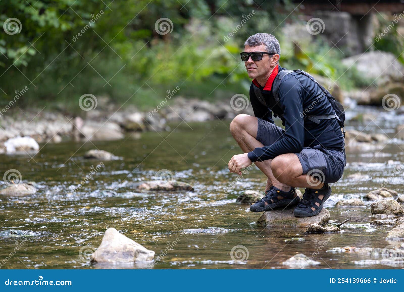 Man Squatting beside River in Forest Stock Photo - Image of leisure ...