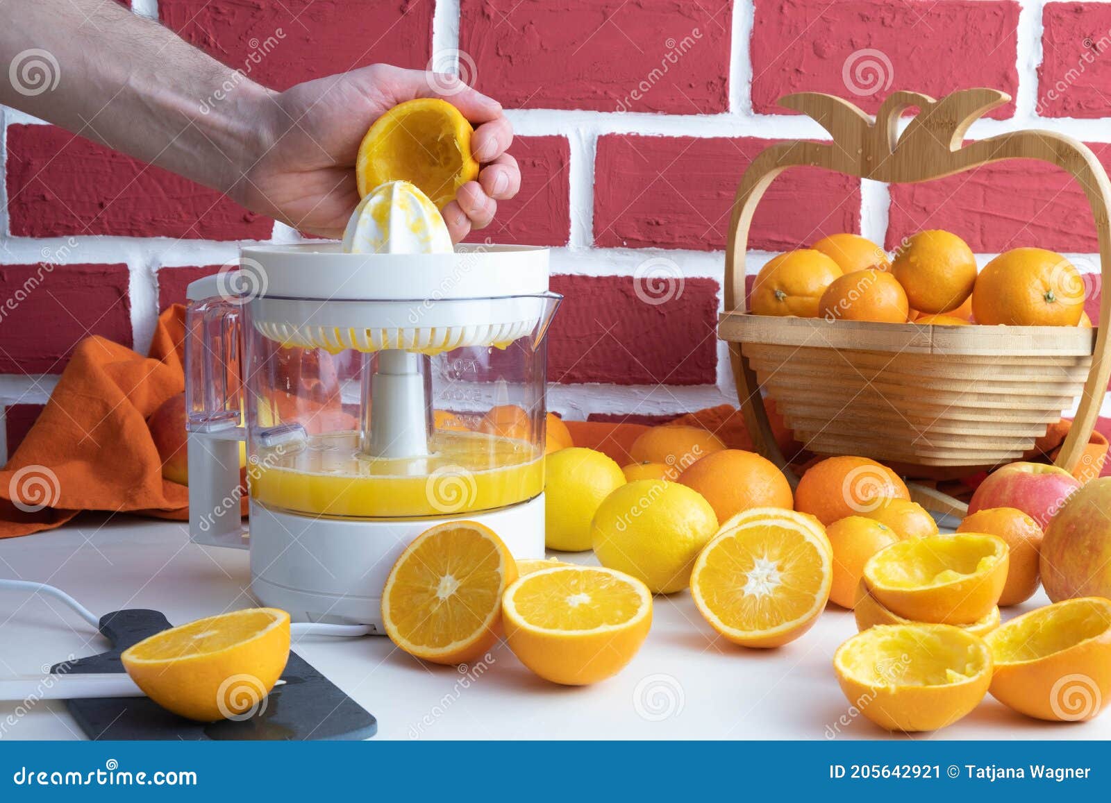 A Man Squeezes an Orange on a White Juicer, Squeezed and Whole Oranges ...
