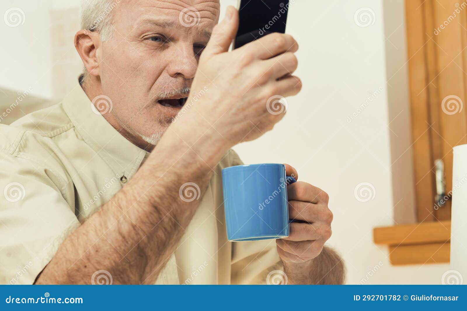 Man Squints at Phone, Breakfasting in Kitchen Stock Photo - Image of ...