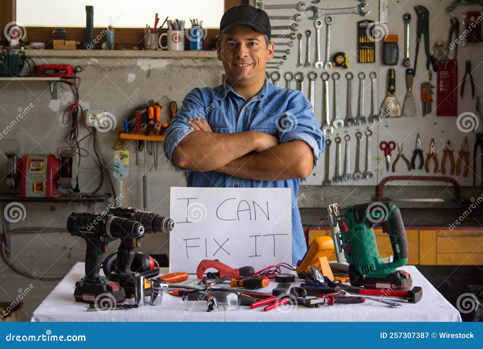 Man Standing Behind a Table with Drills on it with a Writing "I Can Fix ...