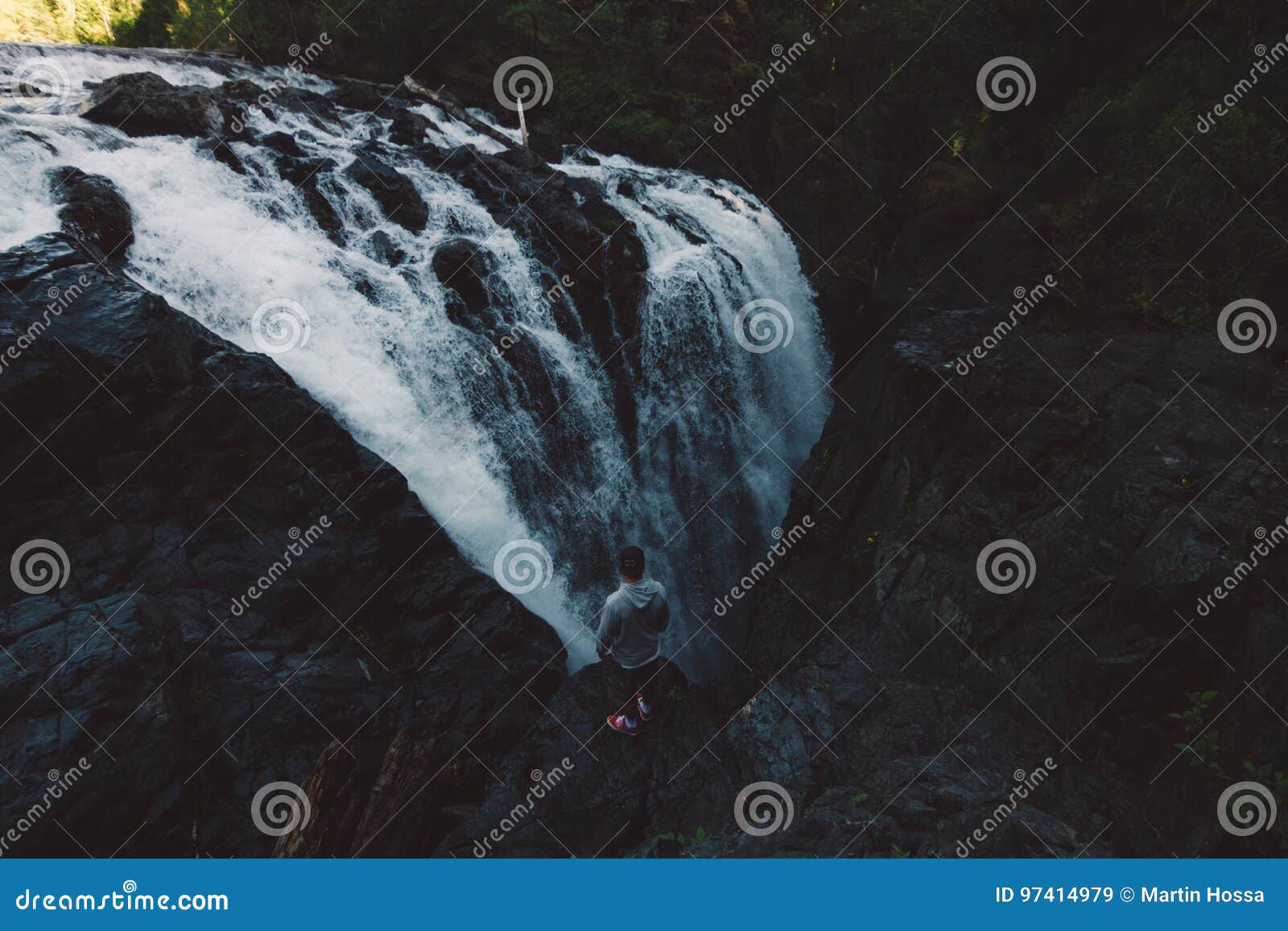 Man Standing on the Edge of the Cliff in Forest with Waterfall Stock ...