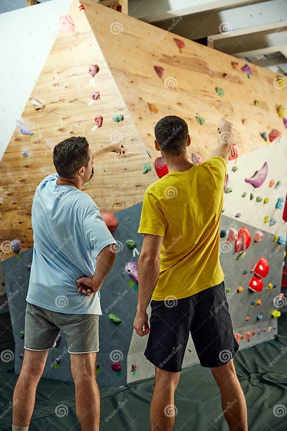 Man Standing with Instructor, Looking and Pointing on Climbing Wall ...