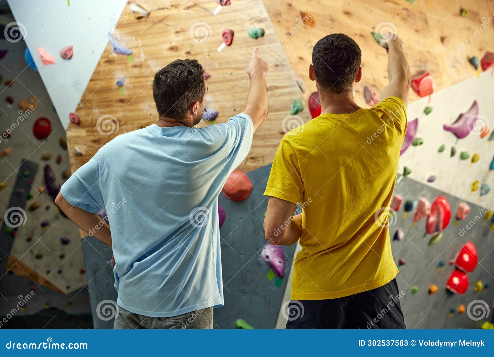 Man Standing with Instructor, Looking and Pointing on Climbing Wall ...