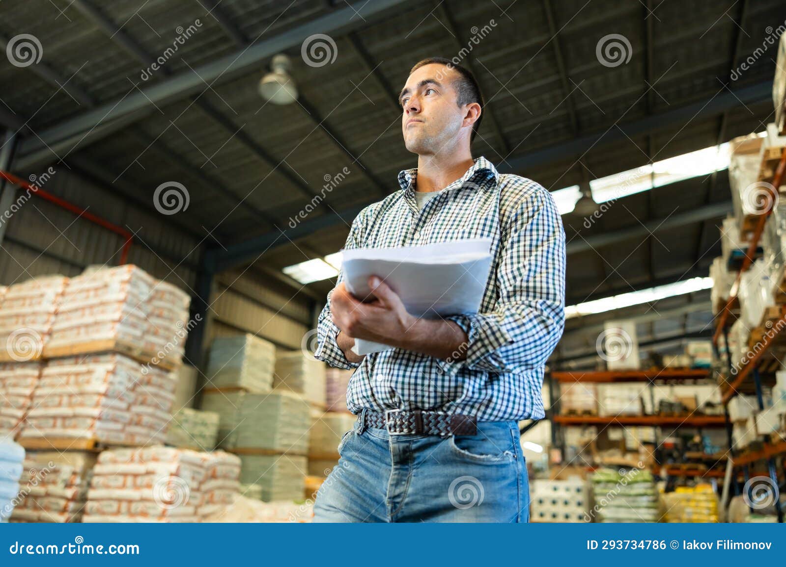 Man Standing in Warehouse and Verifying Documents with Presence of ...