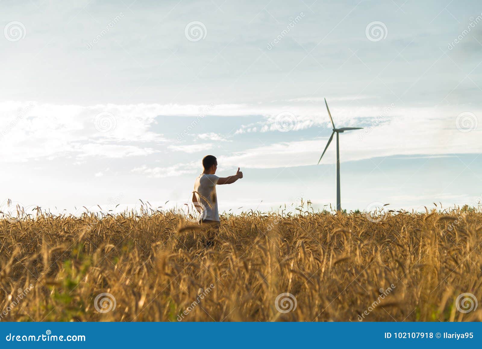A Man Standing in a Field Looking at a Wind Generator Stock Photo ...
